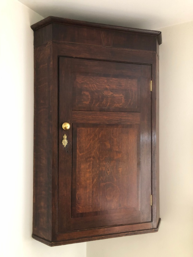 A George III oak hanging corner cupboard, with moulded top, and ...