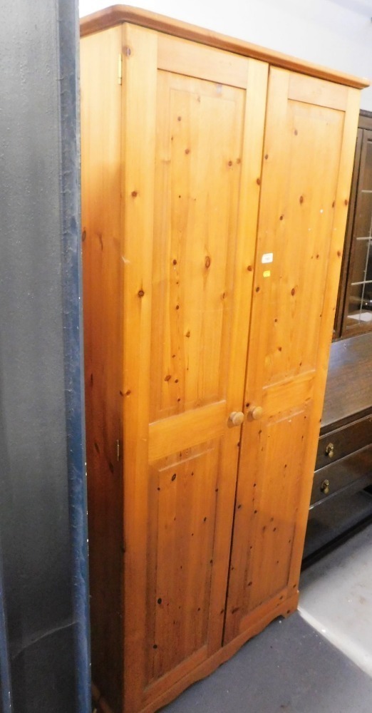 A pine double wardrobe, the top with a rounded edge above two panelled ...