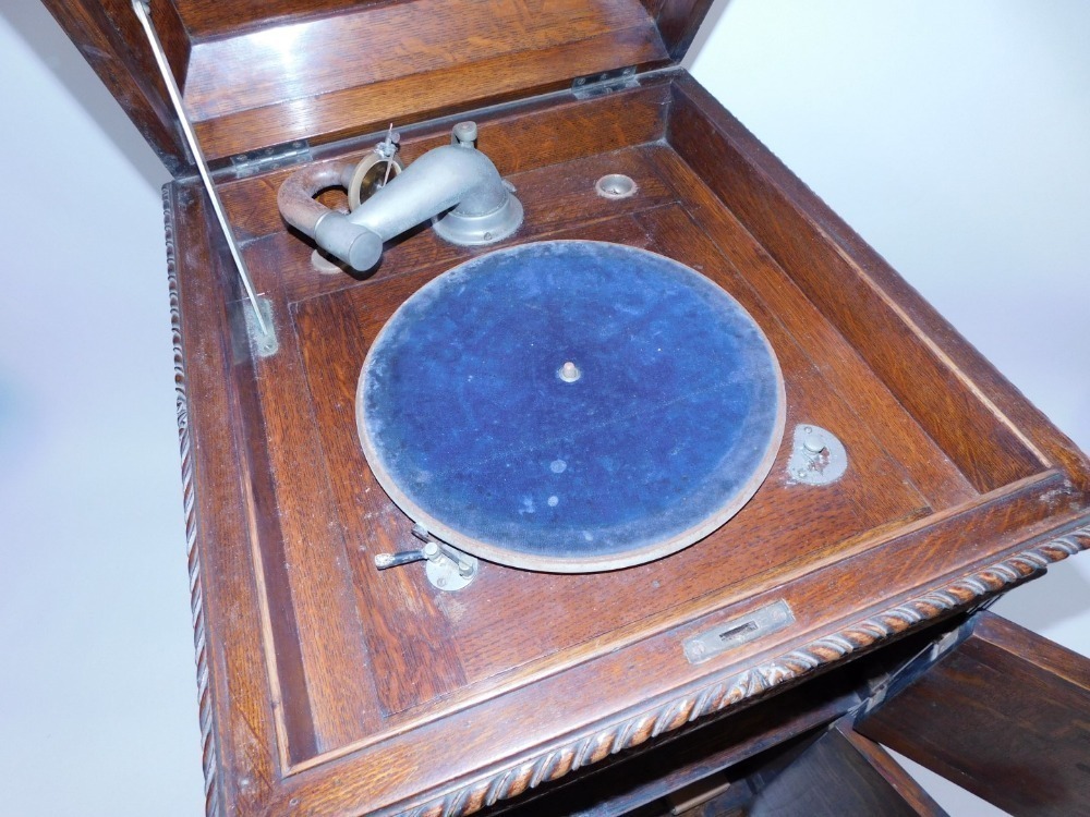 An early 20thC oak cased cabinet gramophone, with record played inset ...