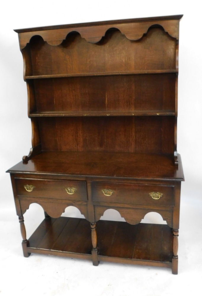 A 20thC oak dresser, with a moulded top above a two shelf plate rack ...