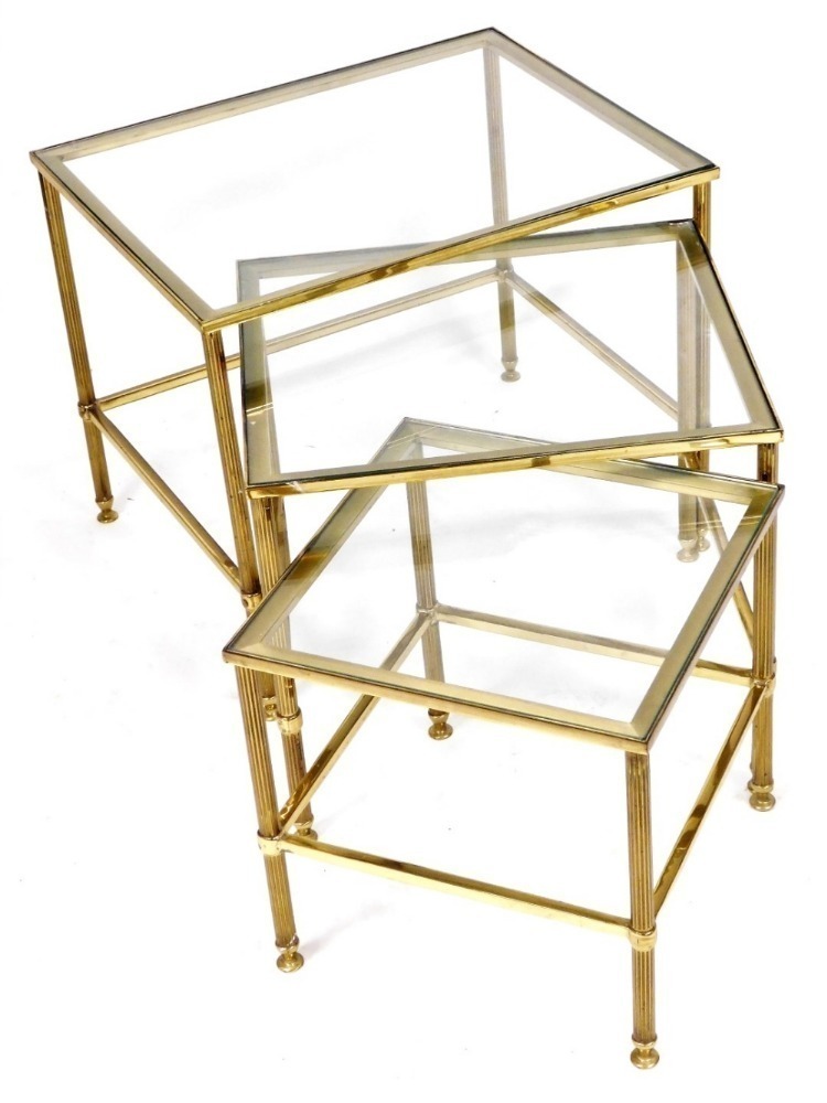 A late 20thC brass nest of occasional tables, with glass tops, raised ...