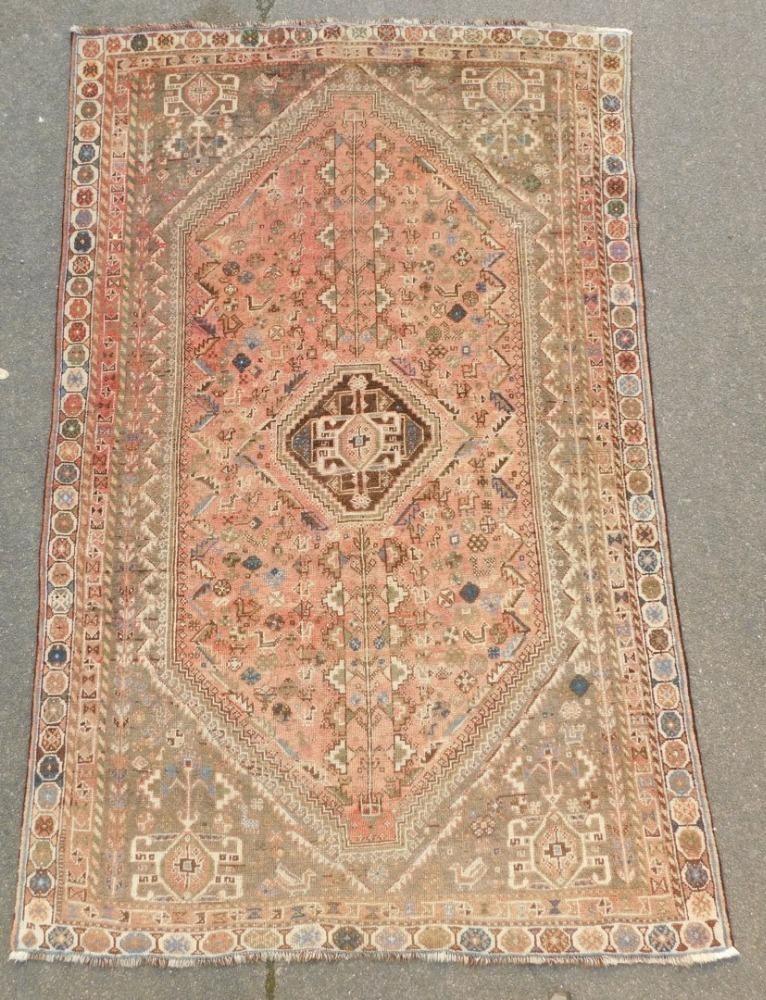 A Persian red ground rug, the central field decorated with a medallion ...