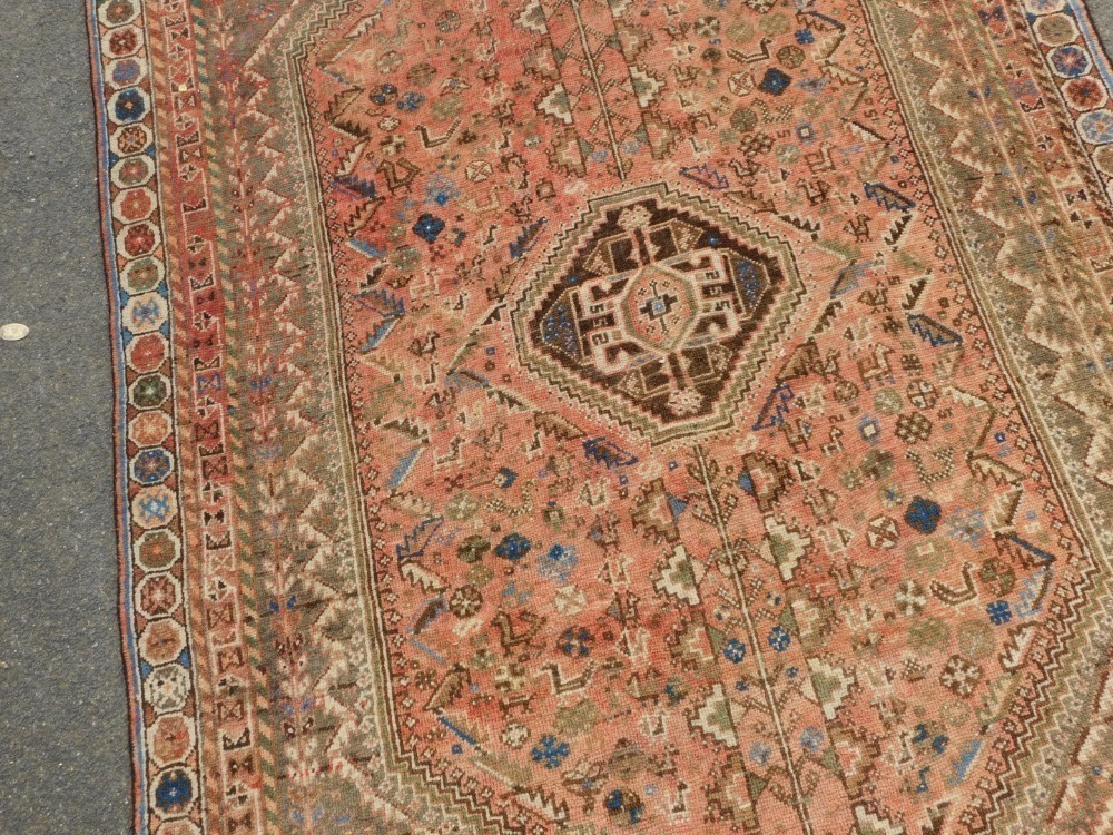 A Persian red ground rug, the central field decorated with a medallion ...