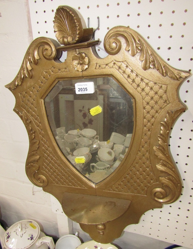 A mid 20thC gilt painted shield wall mirror, with a shell capped top ...