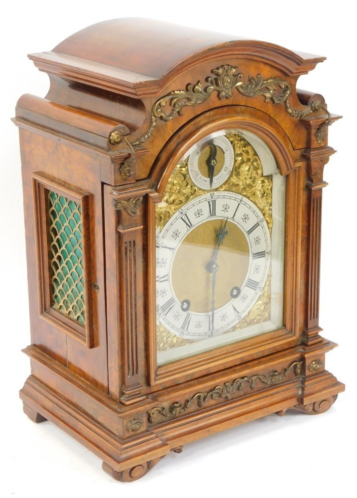 A late 19thC walnut cased mantel clock, with an arched top with brass ...