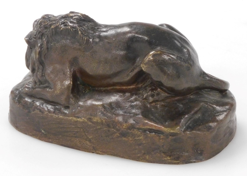 A 19thC cast bronze sculpture of a recumbent lion, on a naturalistic ...