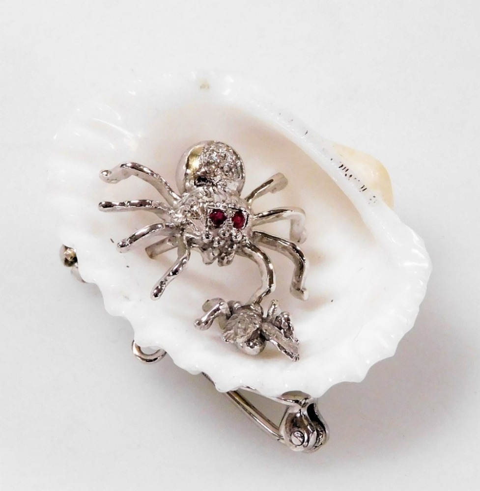 A 9ct white gold and shell form brooch, cast internally with a spider ...