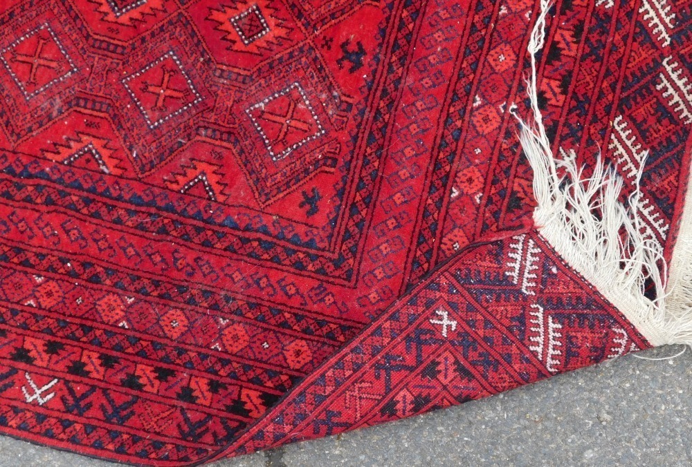 An Afghan red ground rug, decorated with five central bands of ...