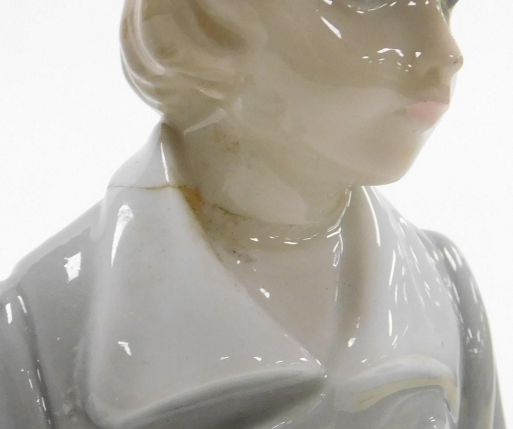 Three Lladro porcelain figures, comprising a boy in a dressing gown ...