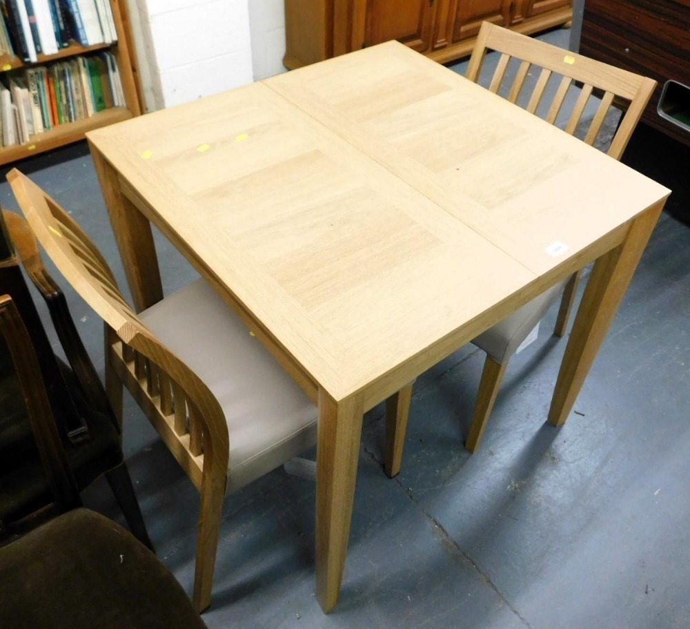 A modern draw leaf dining table and two chairs.