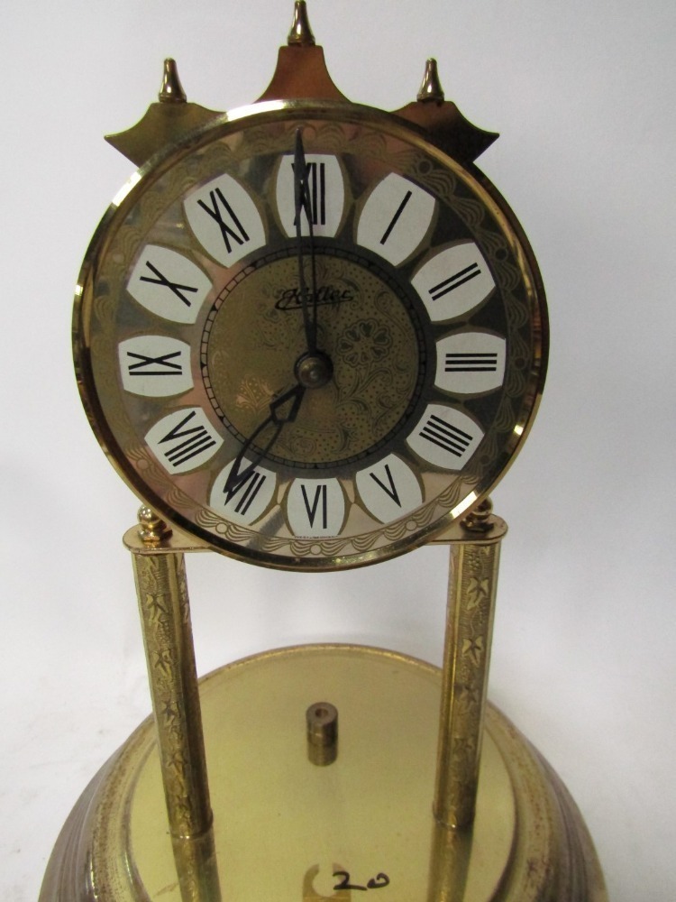 A Kaller brass anniversary clock, with a circular white enamel and ...