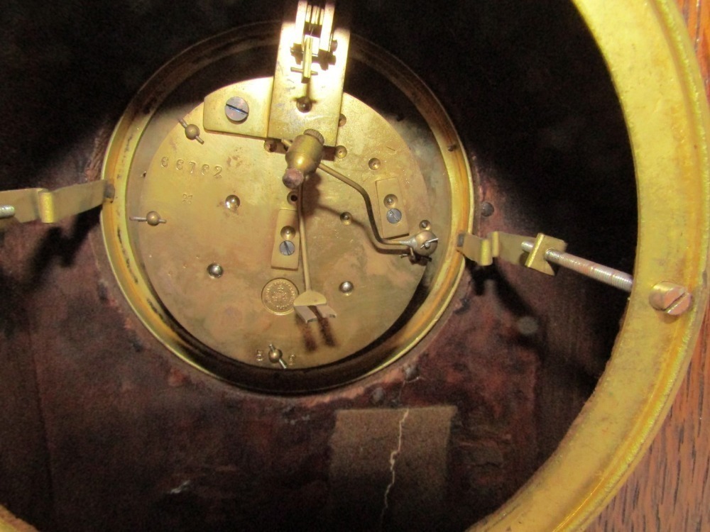 An early 20thC oak cased mantel clock, with a white enamel numeric dial ...
