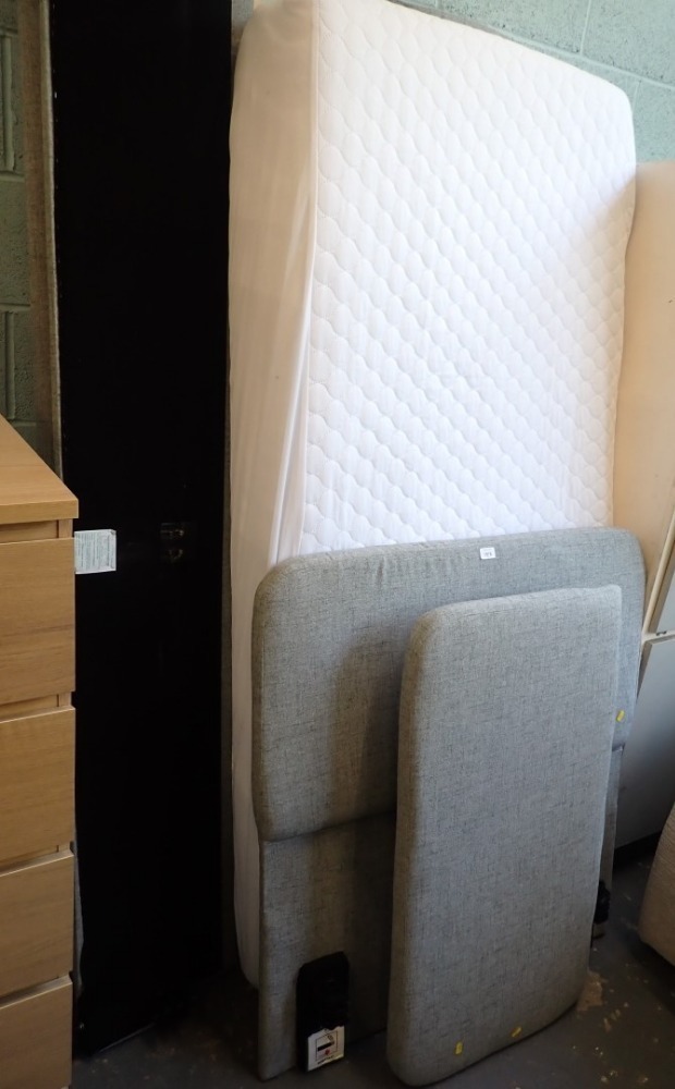 A divan single bed, with grey material base headboard and foot board.