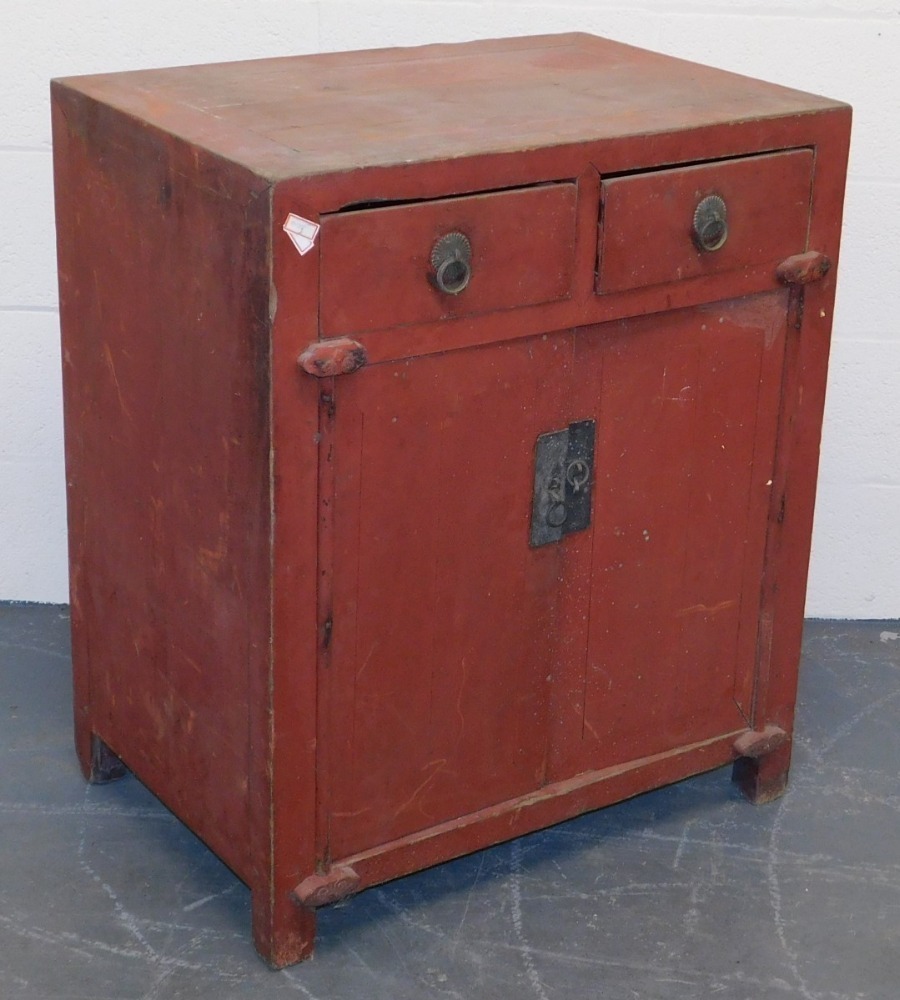 A Chinese red stained cupboard, with two frieze drawers over a pair of ...
