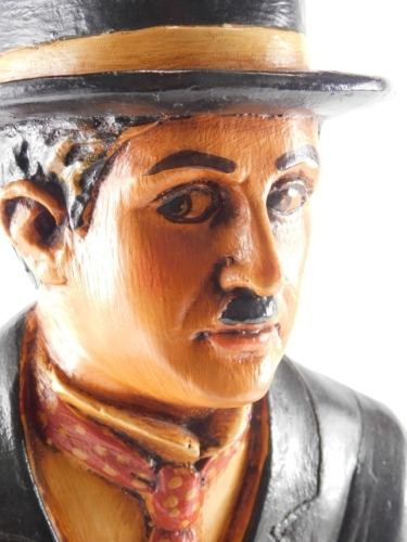 A painted composition figure of a seated Charlie Chaplin, with chair ...