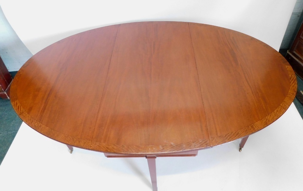 A mahogany oval drop leaf table, with a cross banded border and a ...