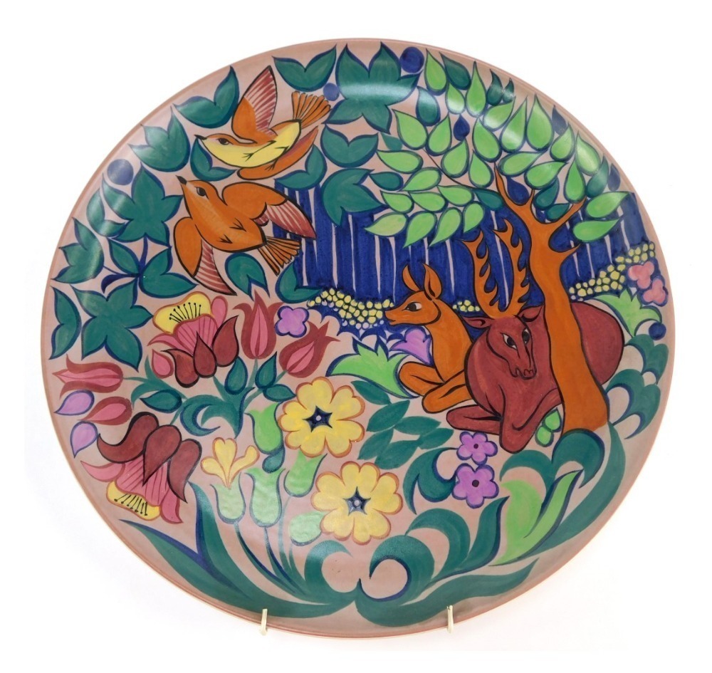 A Poole pottery charger, decorated with stag and deer among trees and ...