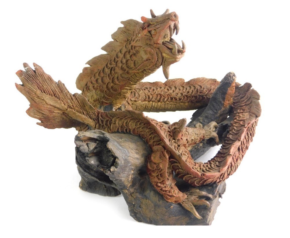 A carved hardwood dragon, arched around log, 22cm wide.
