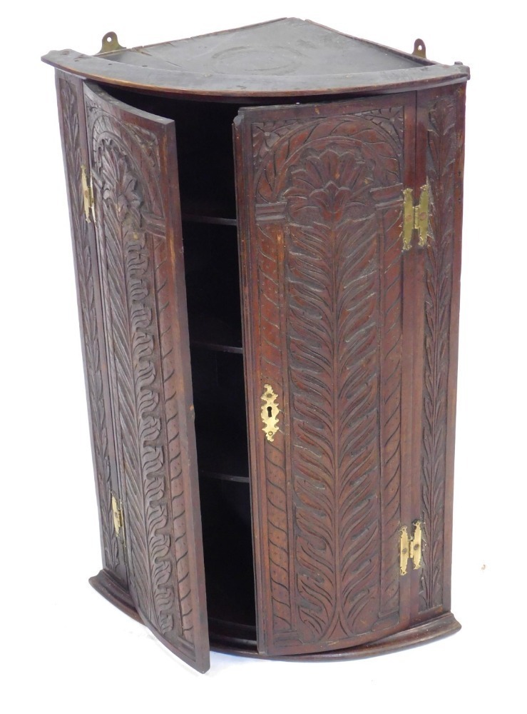 A 19thC carved oak cylinder front corner cabinet, with three shelves to ...