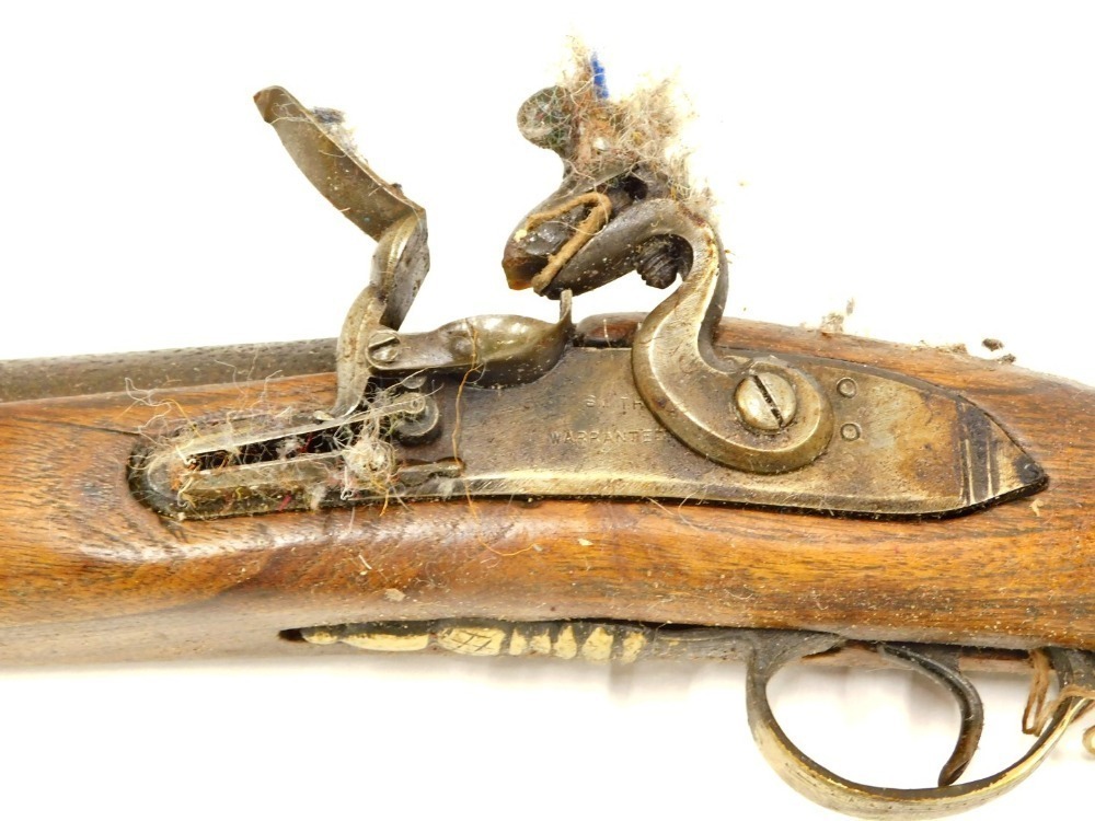 A 19thC left handed flintlock musket by Smith and Co, with brass banded ...