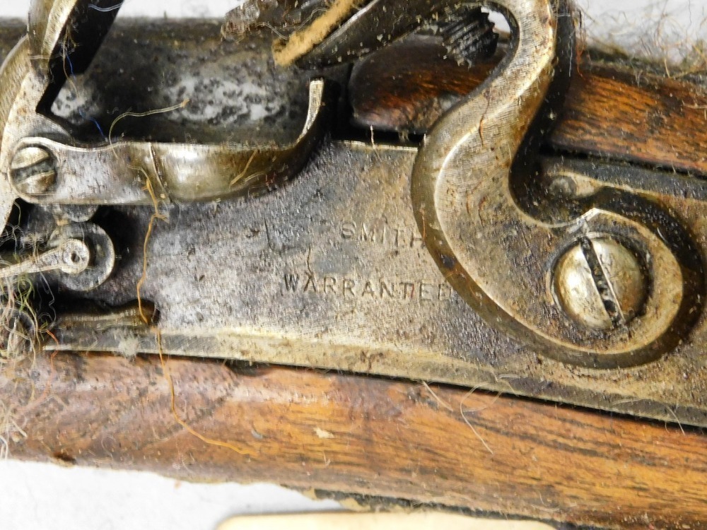 A 19thC left handed flintlock musket by Smith and Co, with brass banded ...