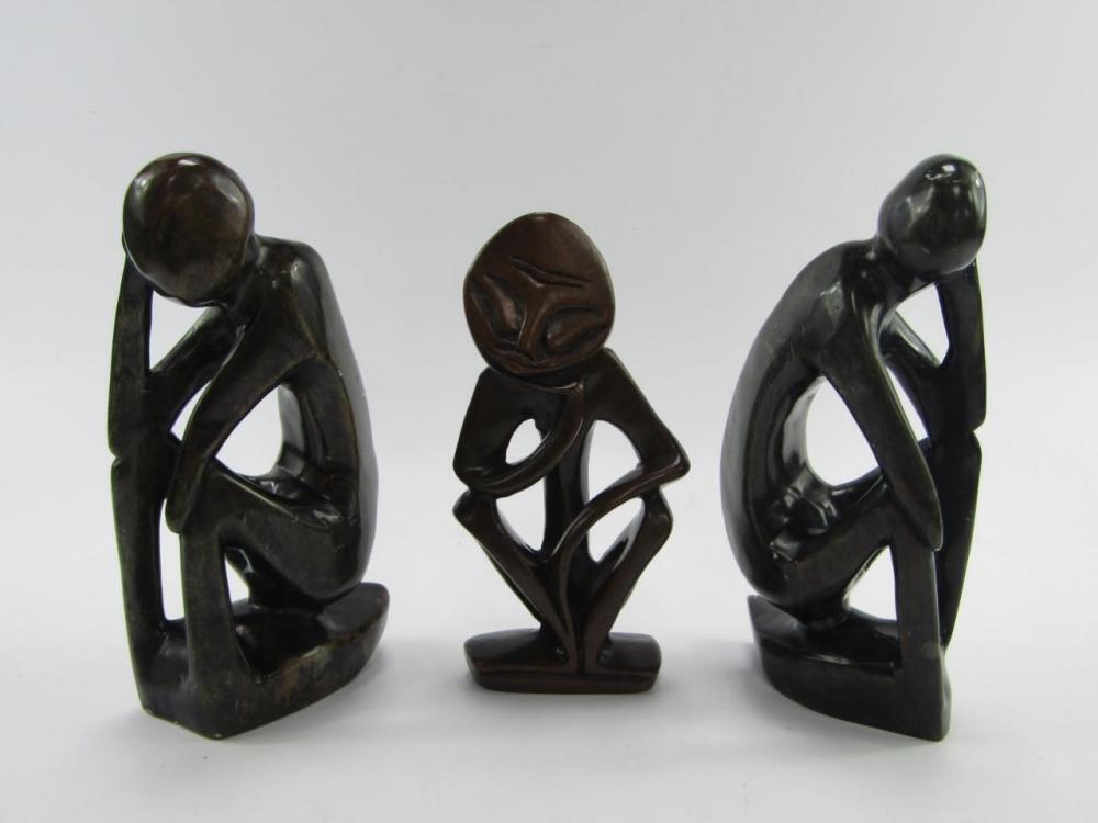 A pair of South African serpentine sculptures of seated figures in ...