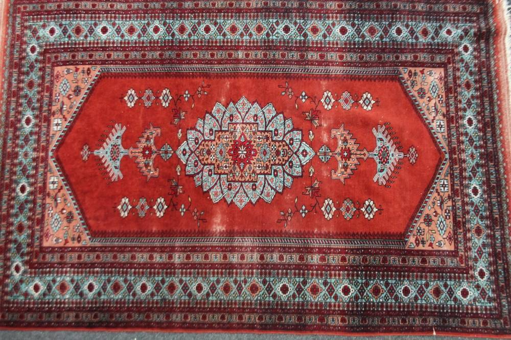 A Middle Eastern rug, in a repeat floral pattern predominately in red ...