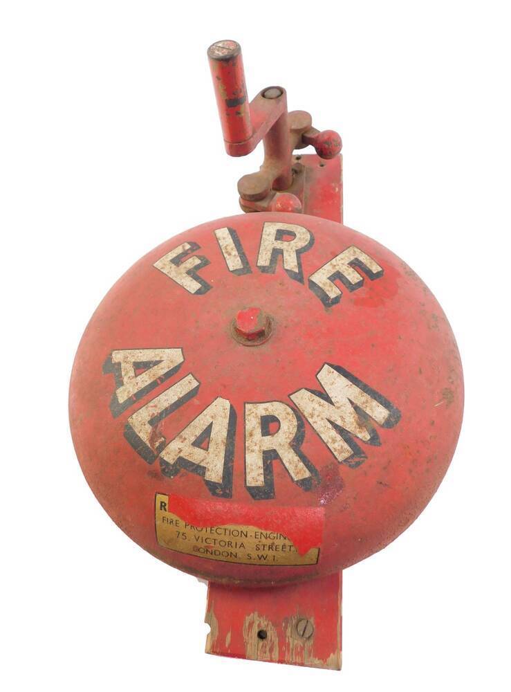 A vintage wall mounted fire alarm, red metal with winder mechanism ...