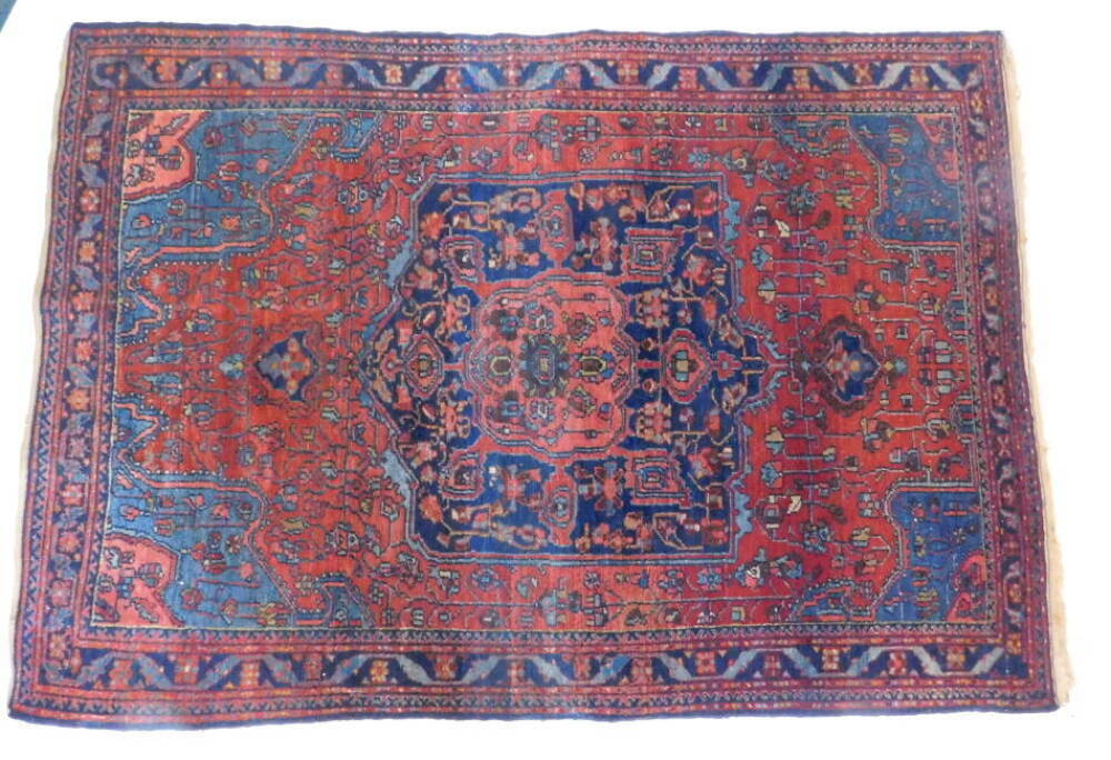 A Persian rug, with a central navy blue and red medallion, pale blue ...