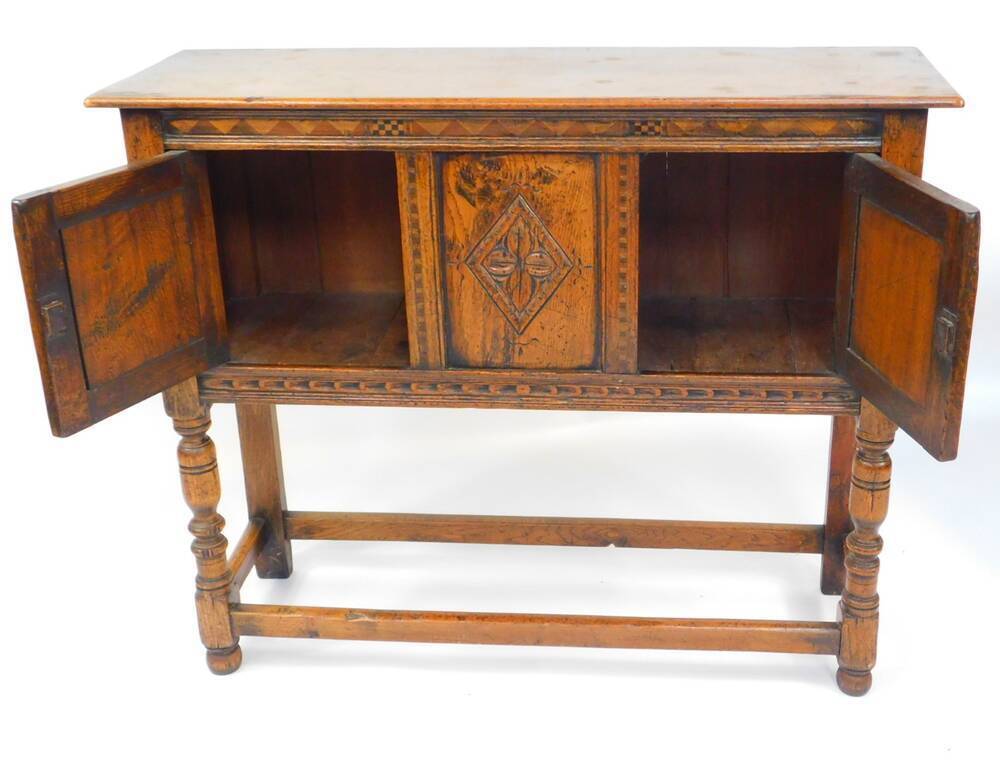 A 17thC style oak sideboard, with a pair of carved panel doors ...