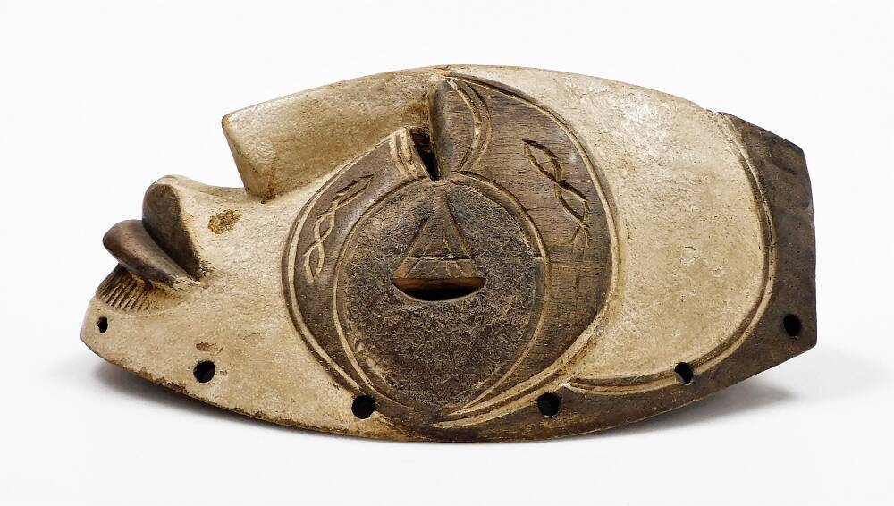 An African tribal face mask, of shaped ellipse form with pierced eyes ...