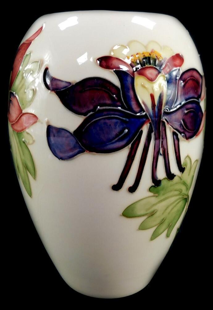 A Moorcroft pottery vase decorated in the Columbine pattern, against a ...