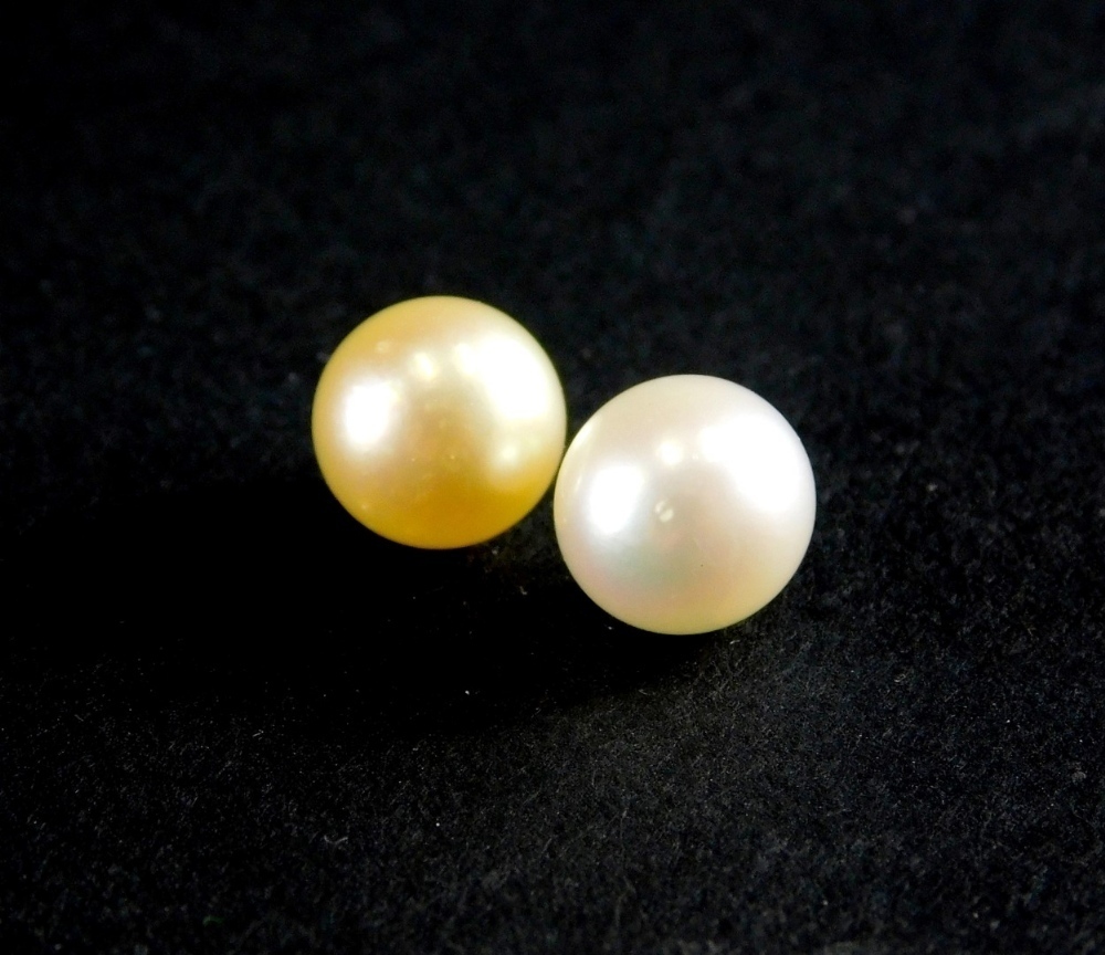Two Mikimoto pearls, mounted in card packaging.