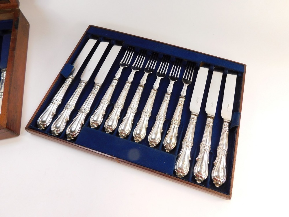 A cased set of twelve silver plated knives and forks, each with a ...
