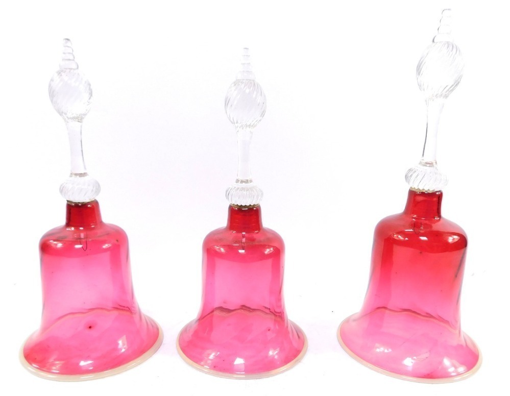 Three Victorian cranberry glass bells, with an opaline base trim and ...