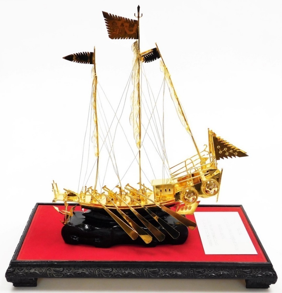 A Chinese gilt metal model of a junk, triple masted with twelve oars ...