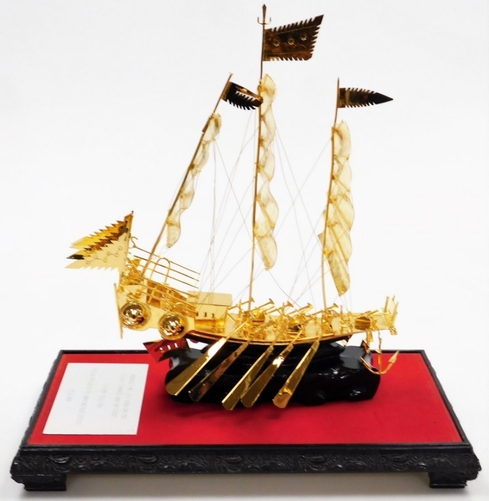 A Chinese gilt metal model of a junk, triple masted with twelve oars ...
