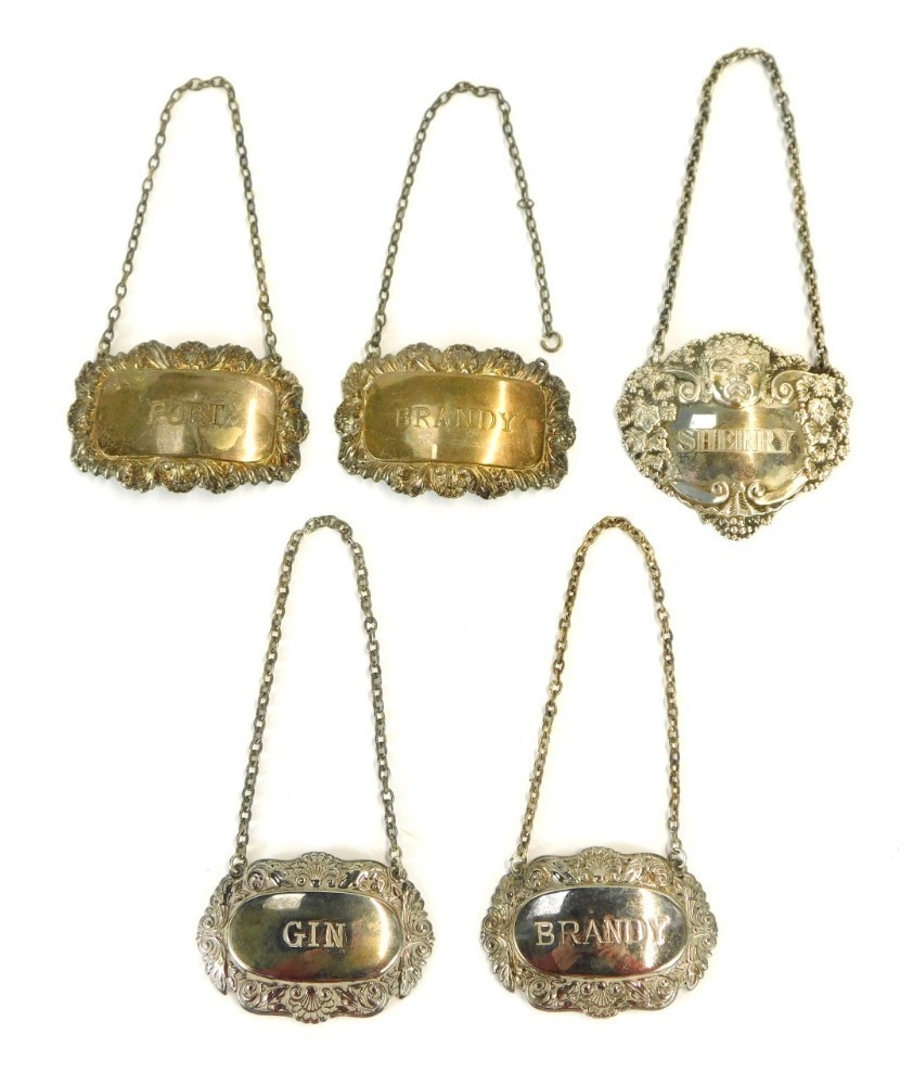 Five decanter labels, comprising three silver labels, one with cherub ...