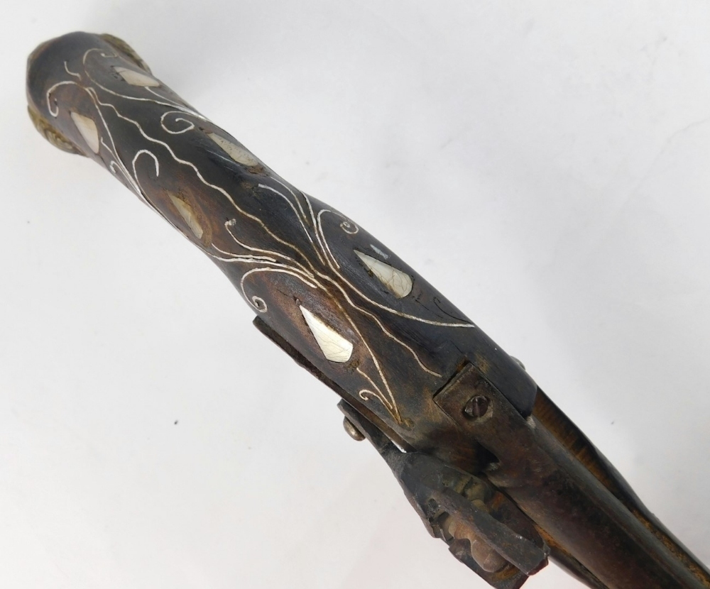 A 19thC Eastern flintlock pistol, with mother of pearl inlay, metal ...
